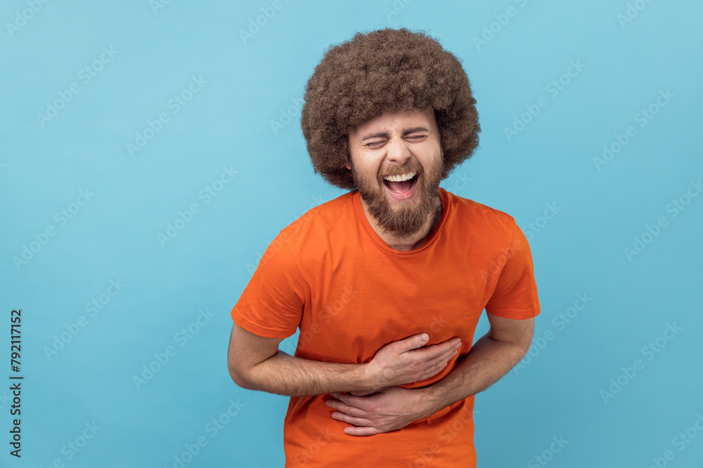 Portrait of laughing man with Afro hairstyle in orange T-shirt holding ...