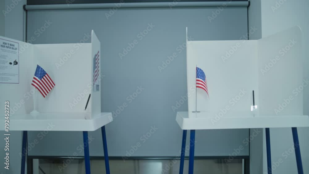 Dolly shot of voting booths with American flag logo in bright polling ...