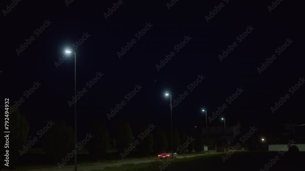At night, street lights illuminate a section of road where the red ...