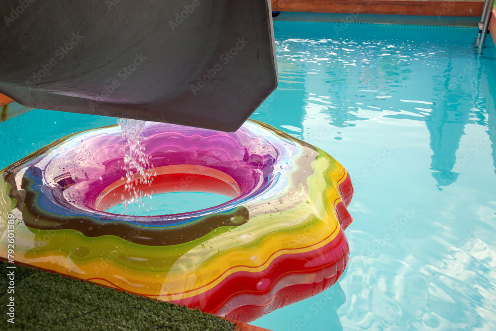 Water flows from a slide into a pool where a colorful inflatable ring ...