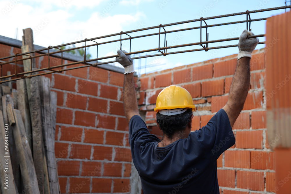 Construction worker carrying an iron beam at a construction site ...