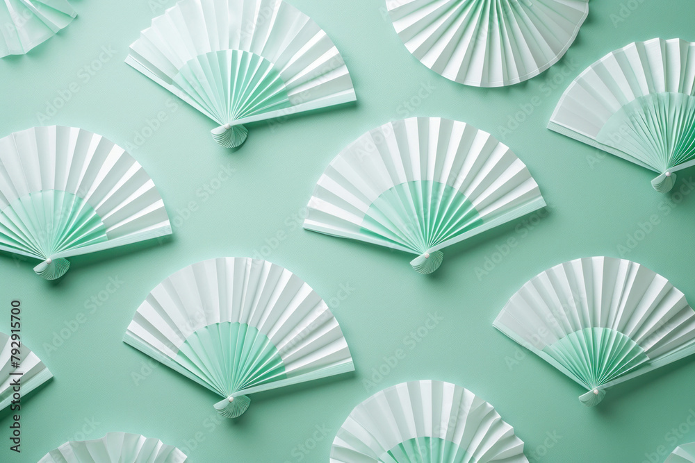 Decorative green and white paper fans arranged on a green wall with a ...