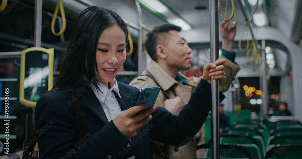 Chinese young girl standing in train or long bus. Using smartphone in ...