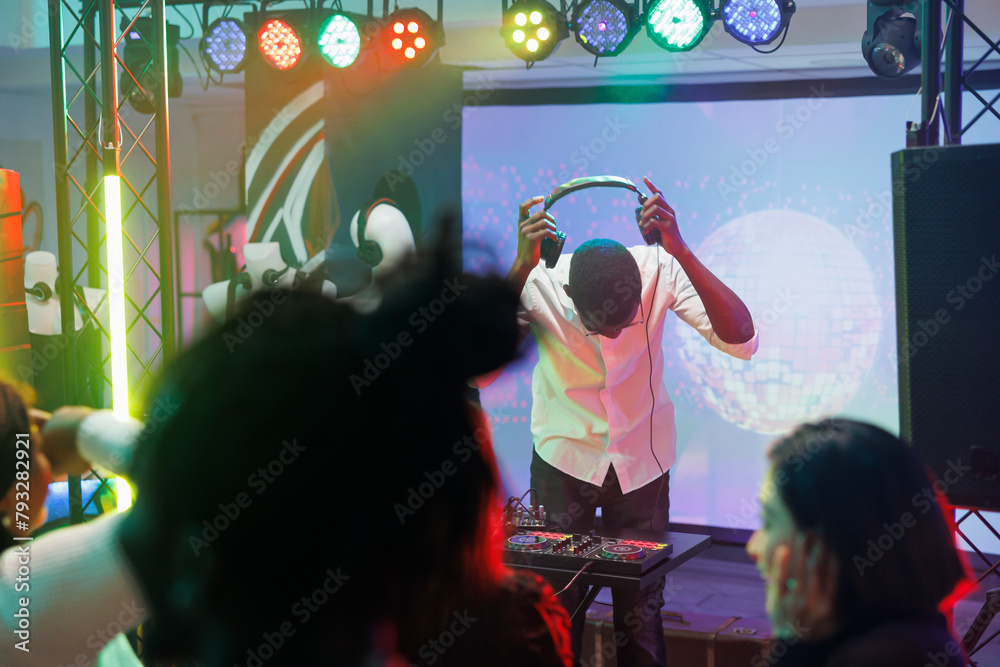 Dj wearing headphones on stage with spotlights during concert live ...