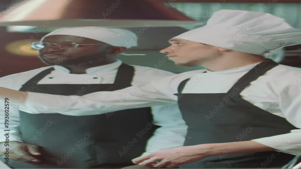 Vertical shot of Caucasian head chef attaching order ticket to rack and ...