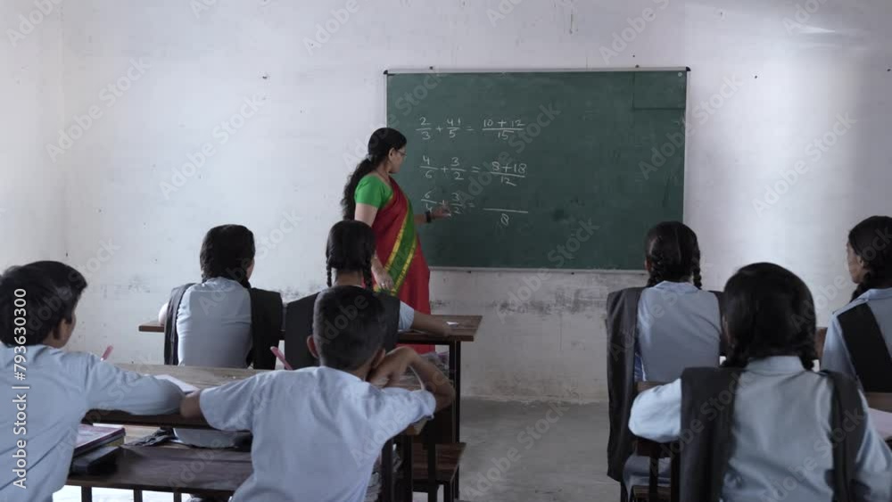 Indian female math teacher writes with chalk on the blackboard teaching ...