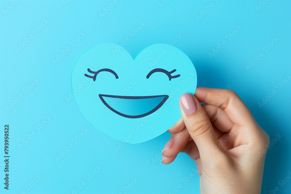 Woman hand holding a happy smile face with heart, blue heart paper ...