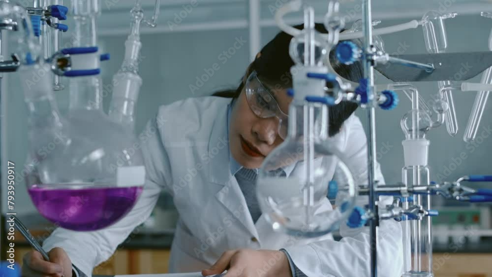 Medium shot of young Chinese female researcher standing at table with ...