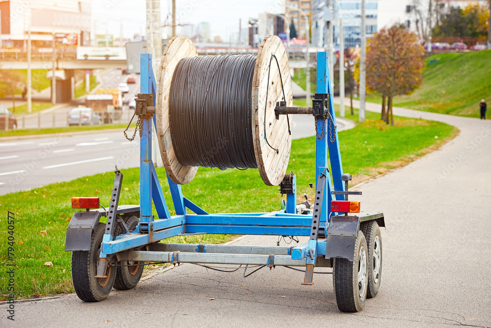 Deploying fiber optic cable. Laying optical cabling from wooden coil ...
