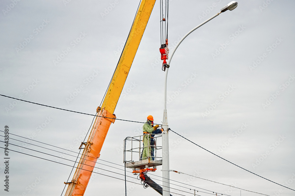 Construction workers in cherry picker welding street light pole. Street ...