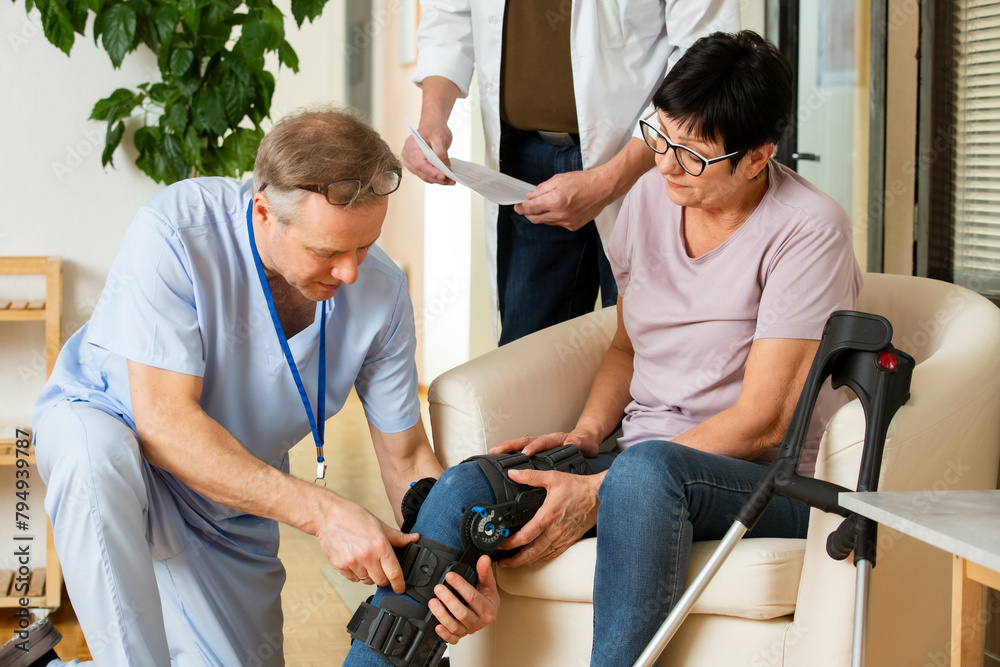 A male nurse helps to put a bondage, medical splint, knee brace on the ...