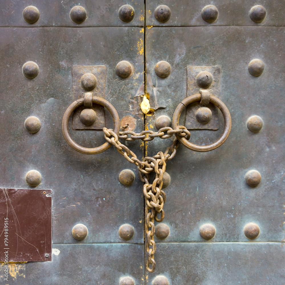 Iron gates with rivets, with two knockers in the form of a ring, tied ...