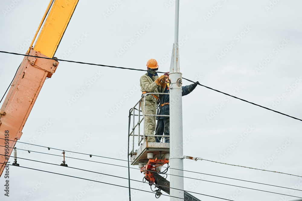 Construction workers in crane bucket welding street light pole. Street ...