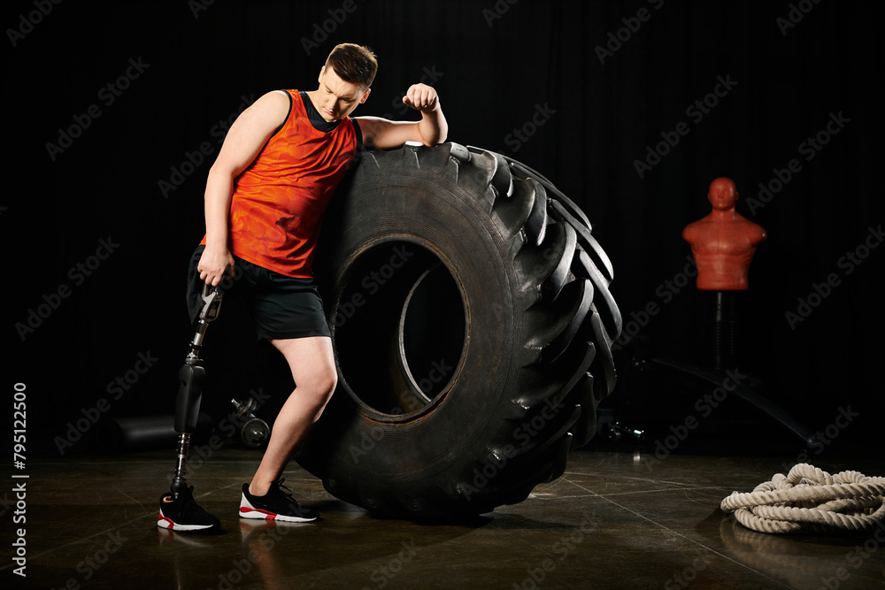 A man with a prosthetic leg stands proudly next to an enormous tire ...