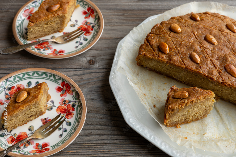 Round cake with almonds, fenugreek seeds, and semolina and two plates ...