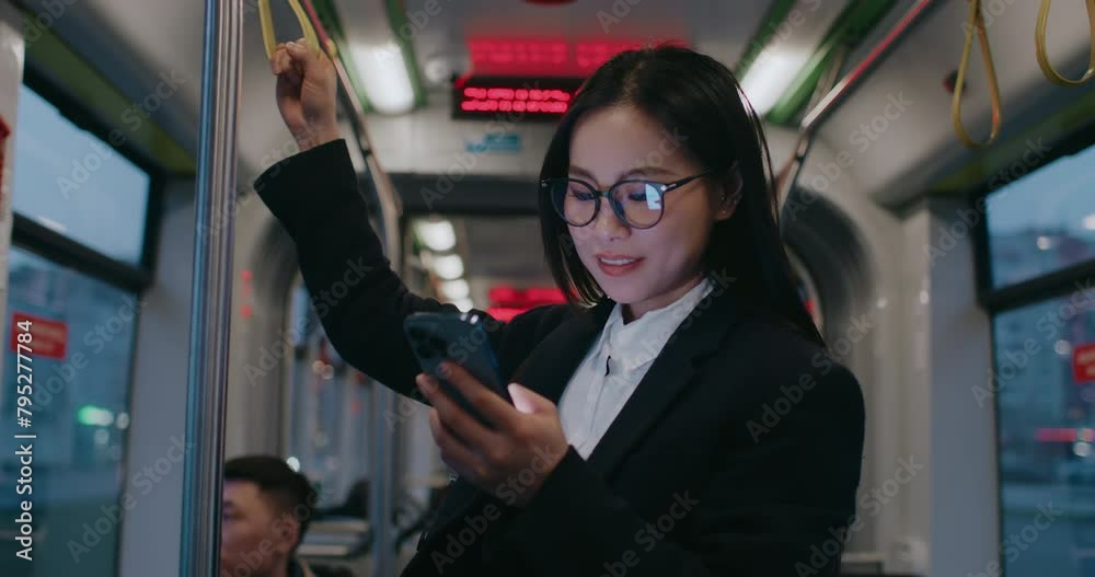 Vidéo Stock Asian woman holding safety handle while scrolling social media on cell phone on her ...