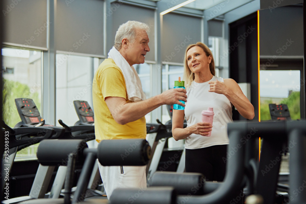Elderly fitness duo shares conversation and hydration after workout at ...
