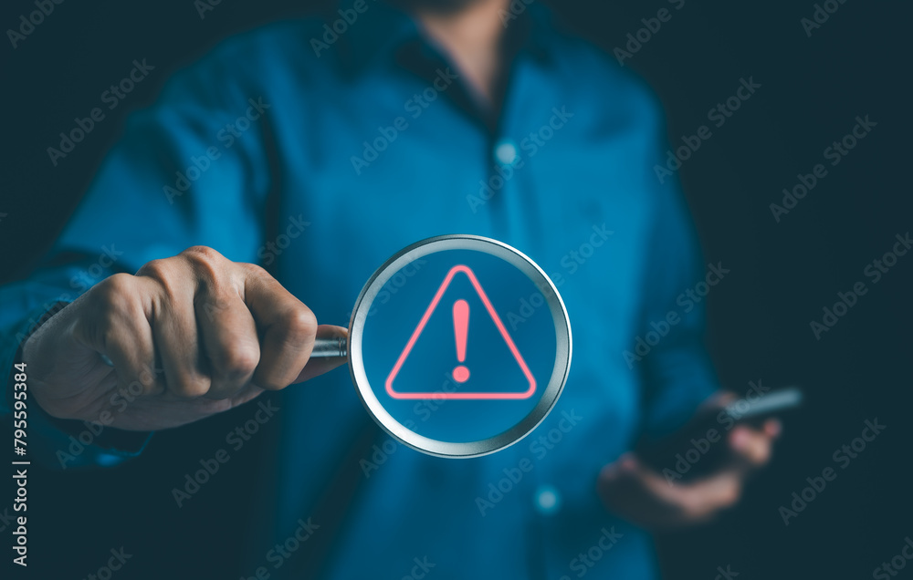 Warning alert system concept. Man holding magnifying glass focused on a ...