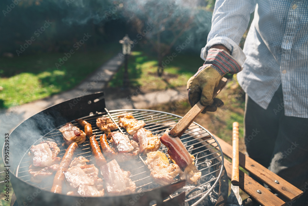 Close up photo of man preparing meat on the grill in his backyard. Male ...