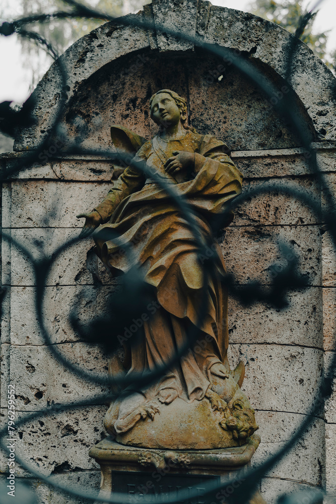 A statue in a cemetery photographed through a beautifully decorated ...
