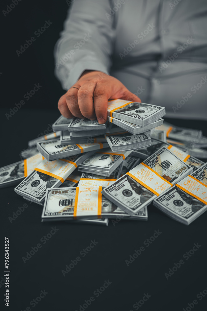 Vertical. A man's hand holds the top of a pile of money on a black ...