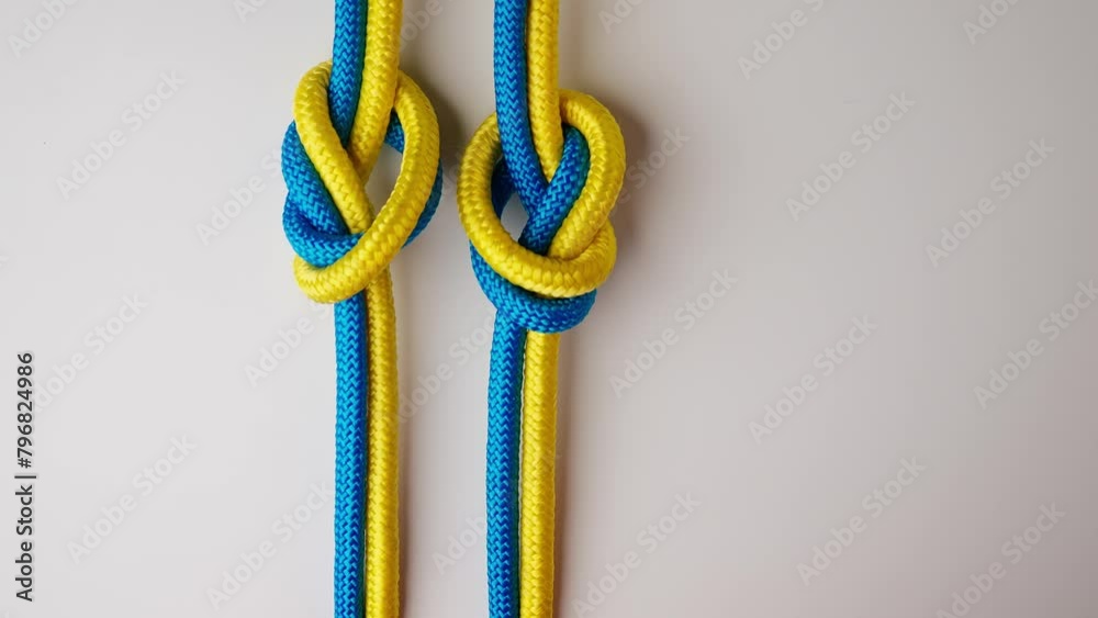 Yellow and blue colored ropes twisted and tied up creating knot ...