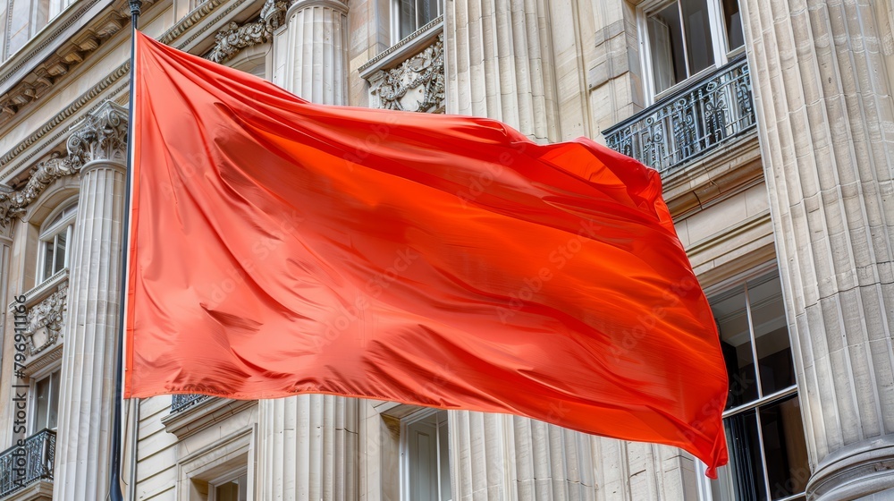 A large red flag waves from the side of a tall building, contrasting ...