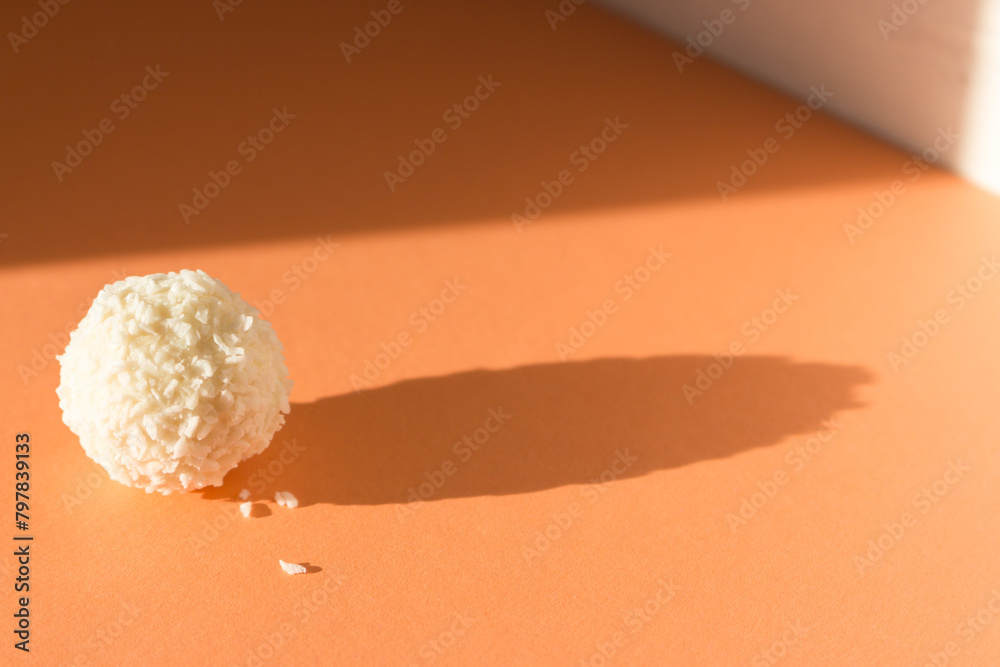 Creamy candy on peach fuzz background. Coconut raffaello on peach color ...