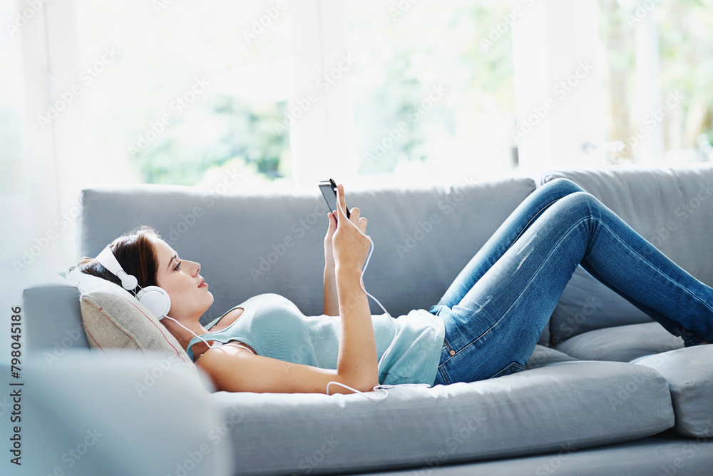 Woman, headphones and phone on sofa in house for music, relax and self ...