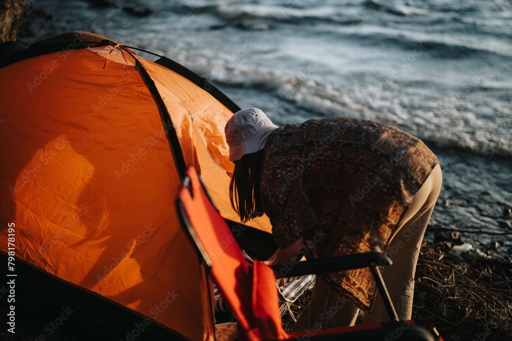 Woman bending over as she sets up a bright orange tent at the ...