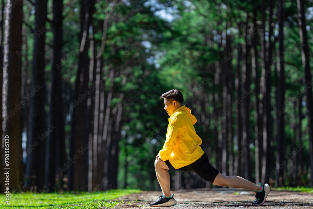 Trail runner is stretching for warm up outdoor in the pine forest dirt ...