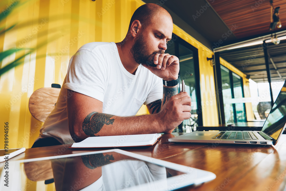 Thoughtful male student concentrated on doing homework task pondering ...