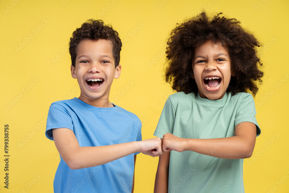 Portrait of two positive kids giving fist bump each other while ...
