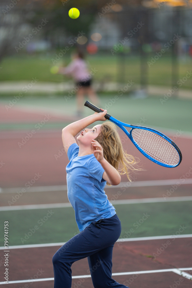 Preteen child swinging racket while training on tennis court at sport ...