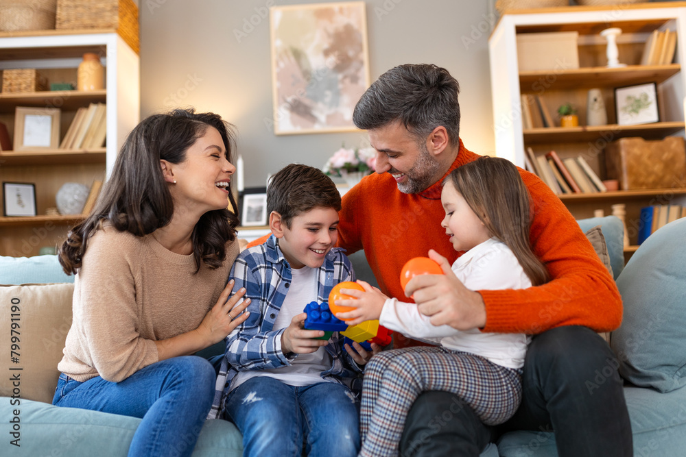 Cheerful son and daughter sitting with parents playing at home. Playful ...