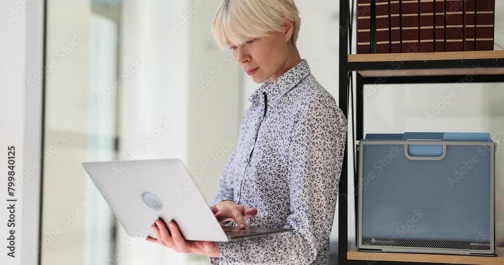 Serious blonde woman employee holds laptop on palm in office. Female ...
