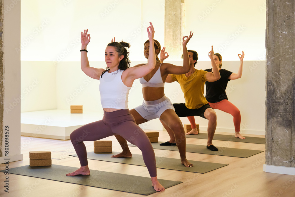 A group of people are practicing yoga, Utkata Konasana or goddess, in a ...