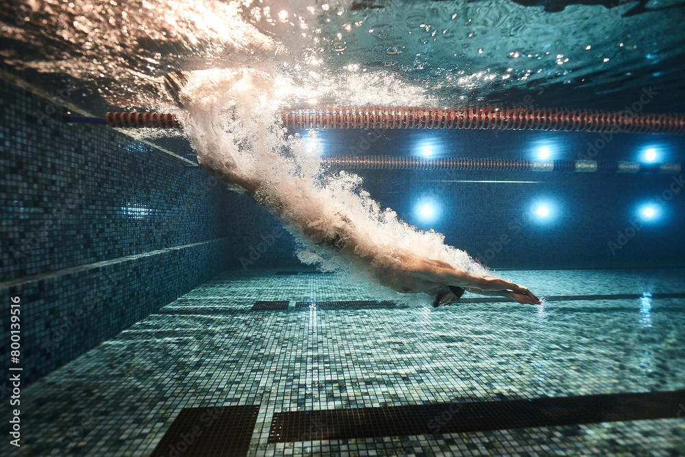 guy swimmer jumps from the side in the pool and dives with a lot of ...