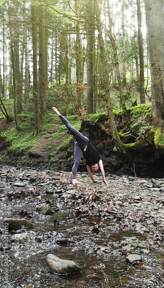 Yoga in nature. Girl in middle of forest conducts a retreat for herself ...