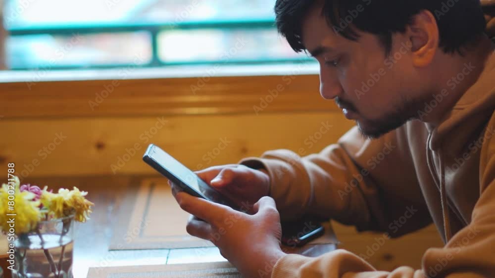 Closeup shot of an Indian man scrolling his mobile phone while sitting ...