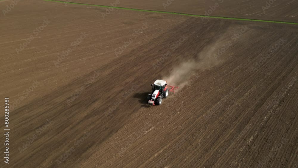 Aerial tracking drone shot of red tractor with white roof plowing and ...