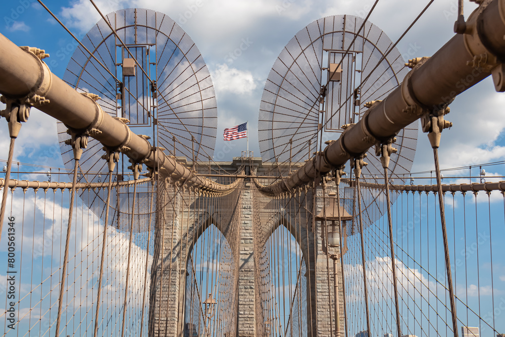 The gate of Brooklyn Bridge with a waving American flag on top of it ...