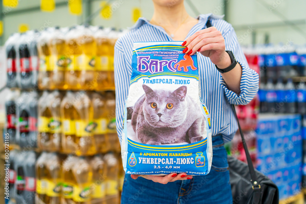 Woman is holding a bag of cat litter with a picture of a cat on it ...