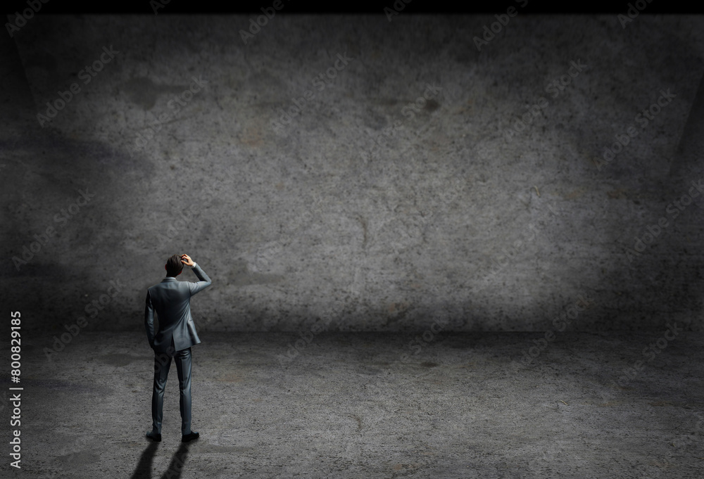 man in suit inside an empty room with concrete grey wall and floor ...