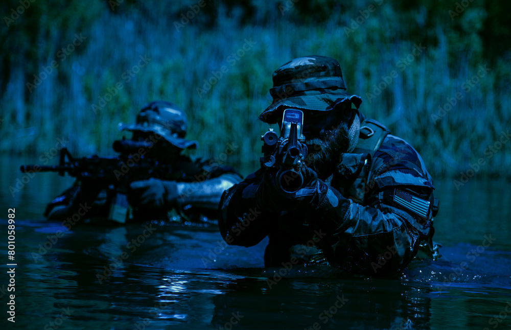 Soldiers move in the heart of a marsh, crossing swampy waters, tropical ...