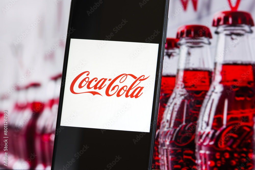 Coca-Cola company logo on screen of smartphone against blurred ...