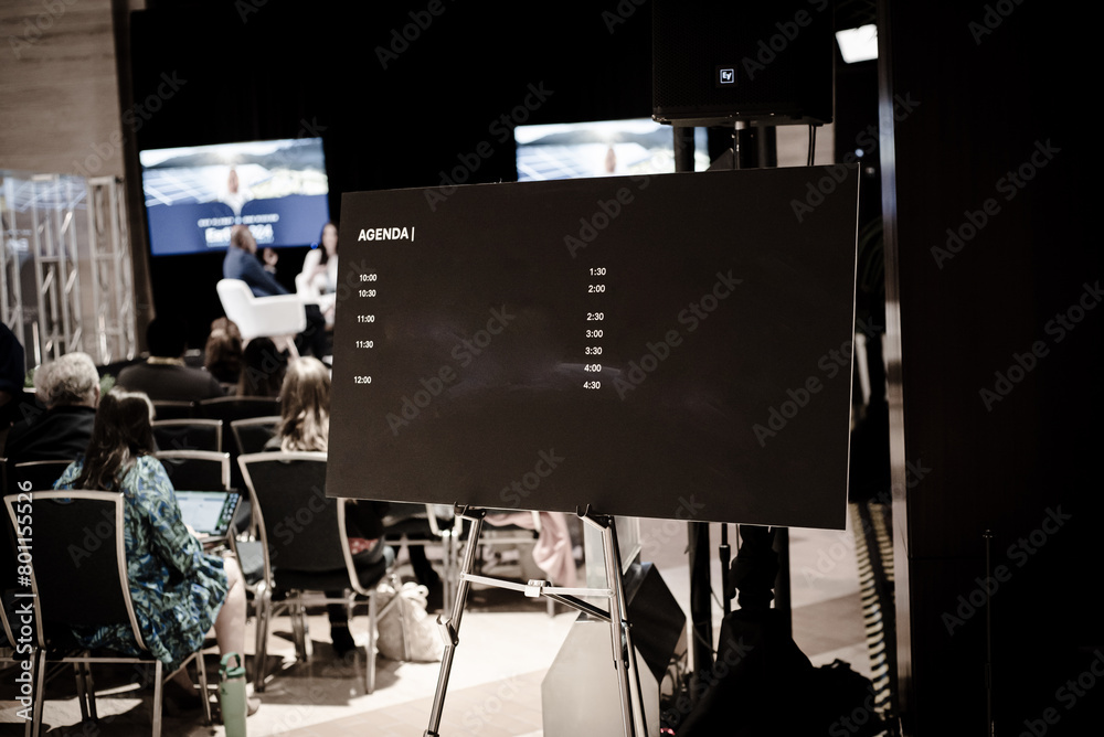 Blank meeting agenda template on telescoping display easel with blurred ...