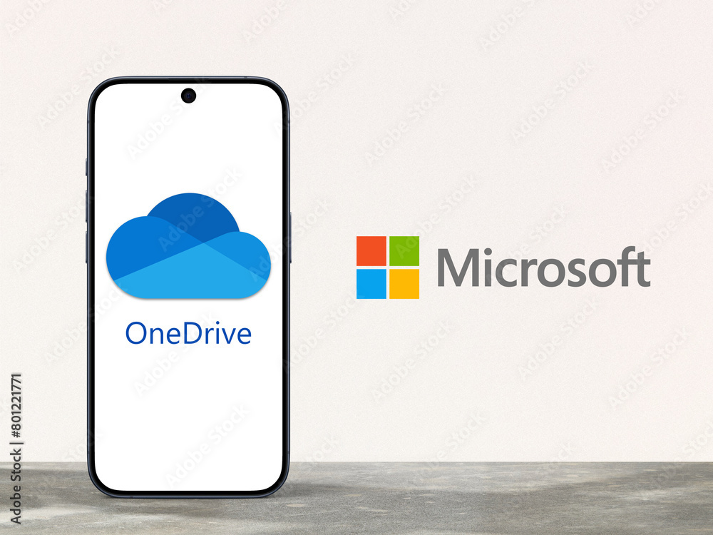 OneDrive logo displayed on a modern smartphone standing on a desk ...