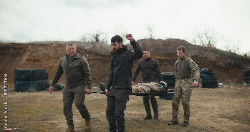 Side view of four confident military men in green uniforms carrying a ...