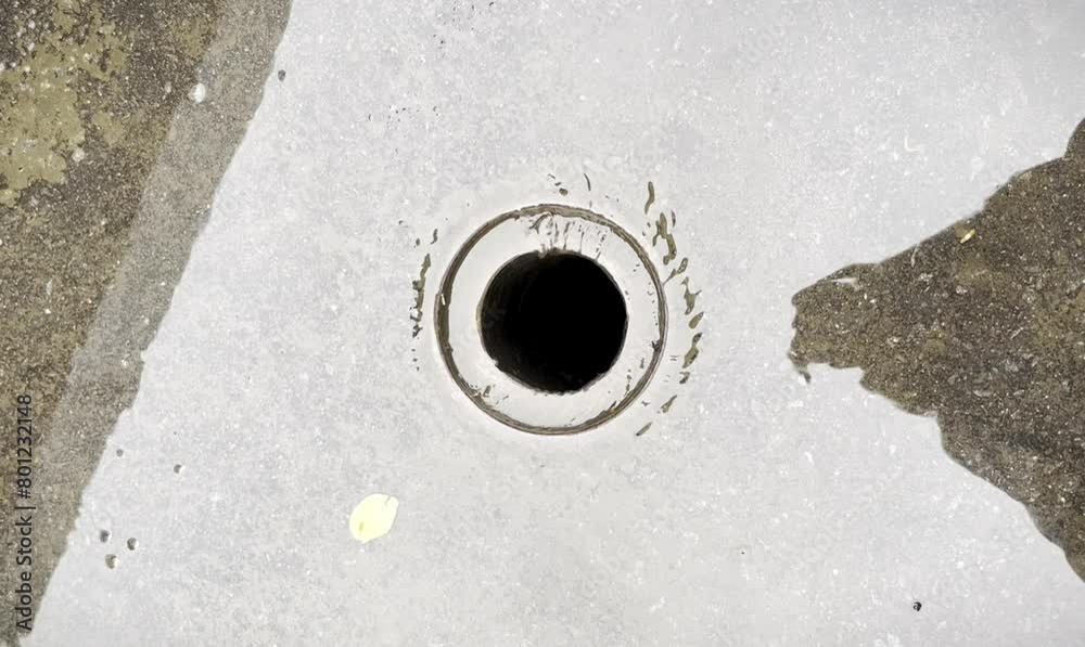 Rain water puddle flood flowing into small round outdoor street metal ...